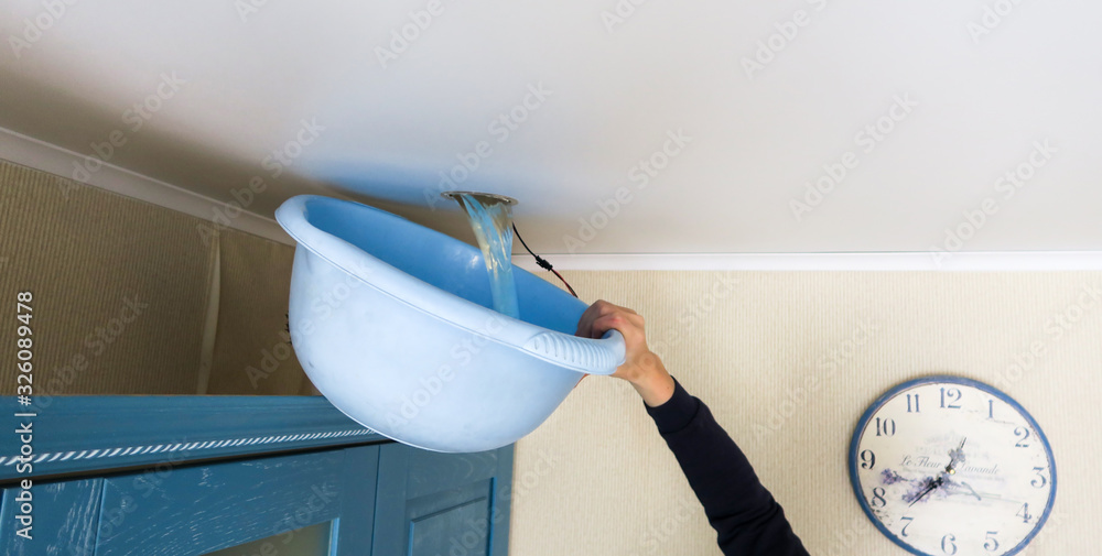 A woman drains water from the stretch ceiling through the hole for the ...
