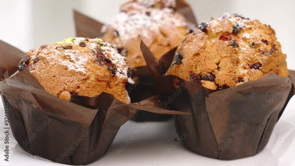 Close up fresh muffins with raisins covered by powdered sugar rotating ...