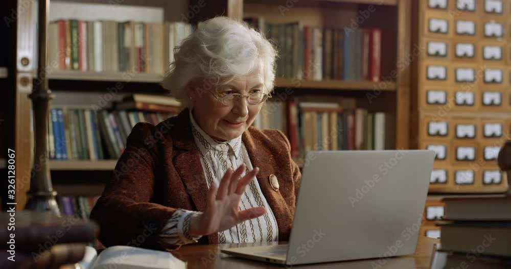 Curious Caucasian old gray-haired woman sitting at table in library and ...