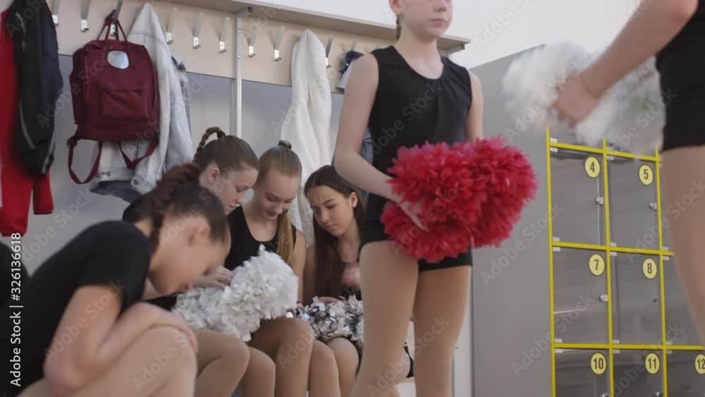 Handheld tracking of teen and preteen girls with pom-poms waiting ...