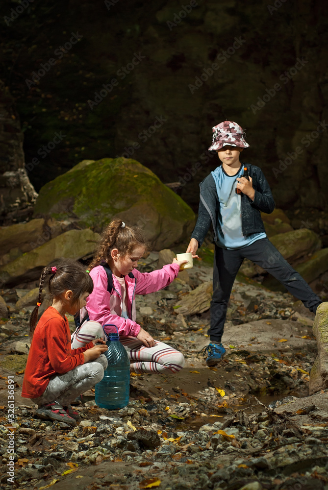 Children pump water into a plastic bottle. Girl draws water from a ...