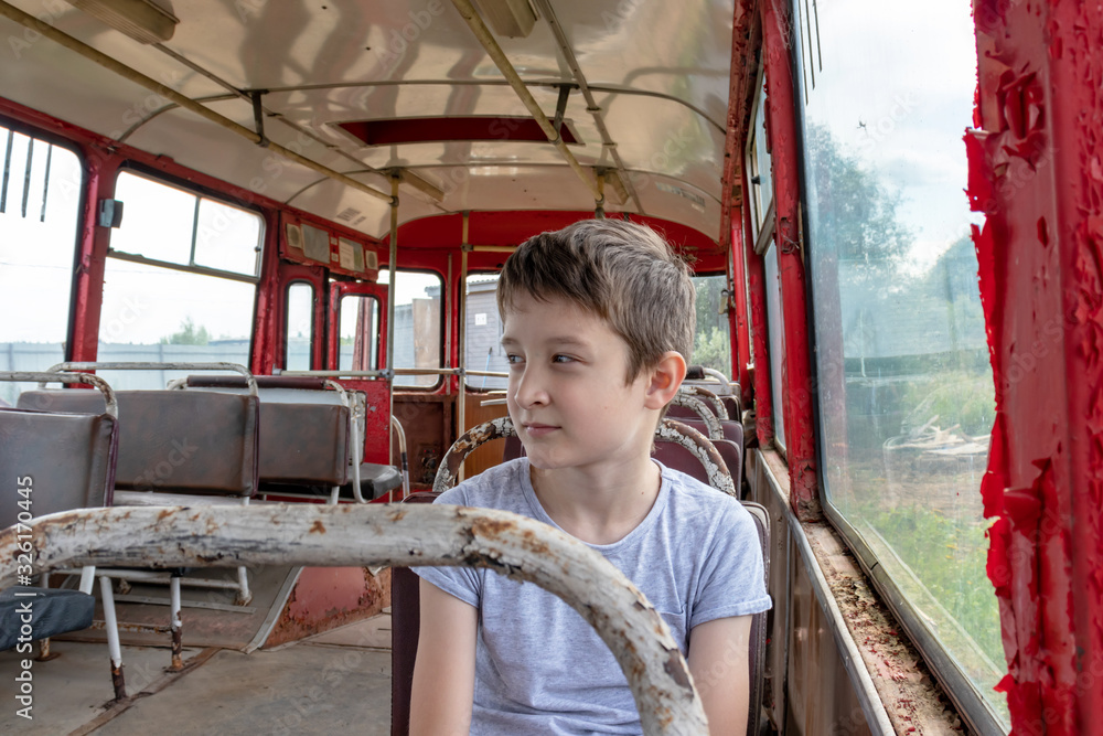 A 10 years boy riding in a old vintage bus, he is sad because his poor ...