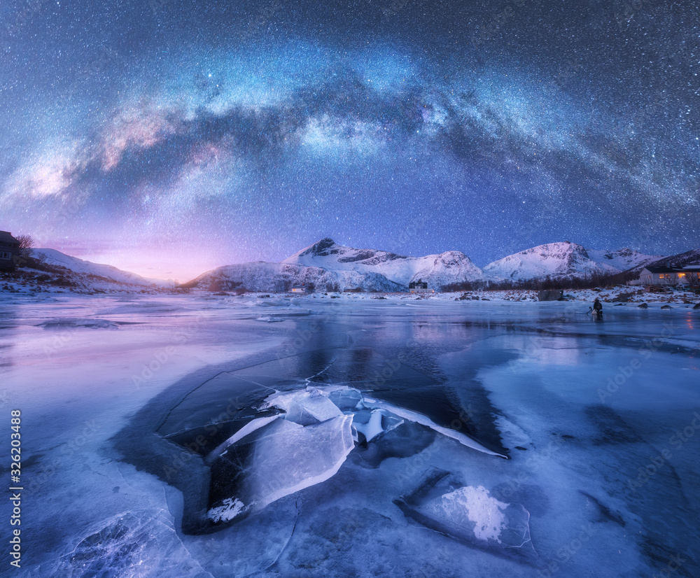 Milky Way above frozen sea coast and snow covered mountains in winter ...