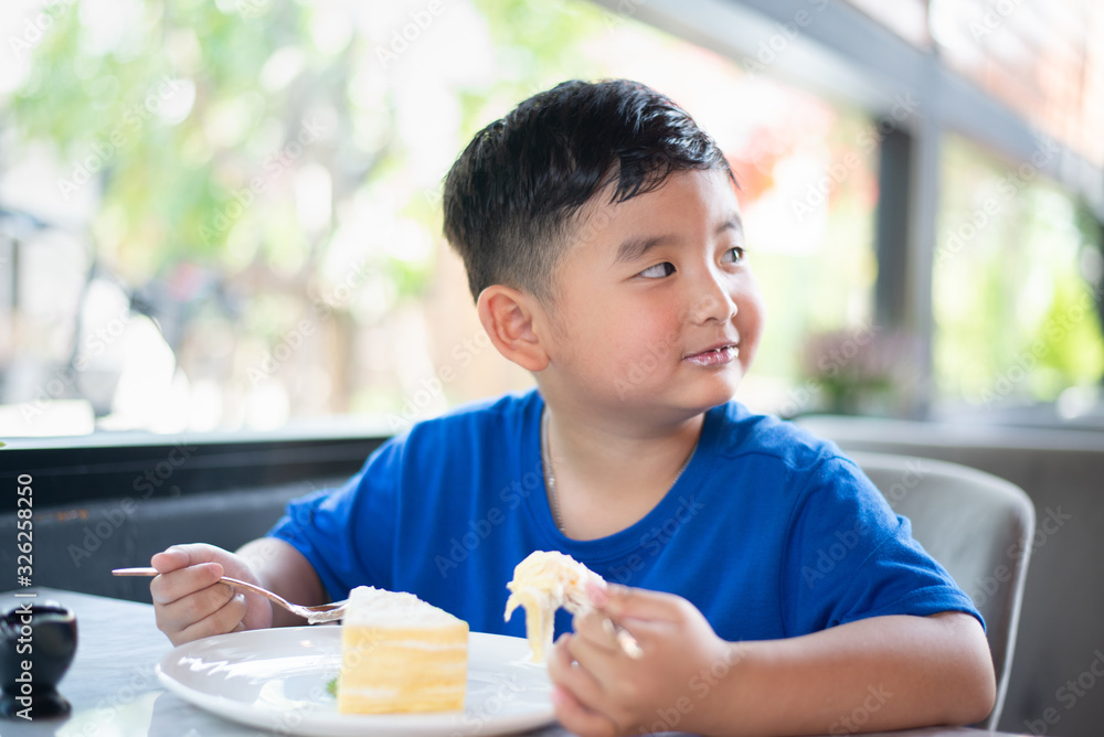 Asian boy eating cake in bakery shop or cafe. Stock Photo | Adobe Stock