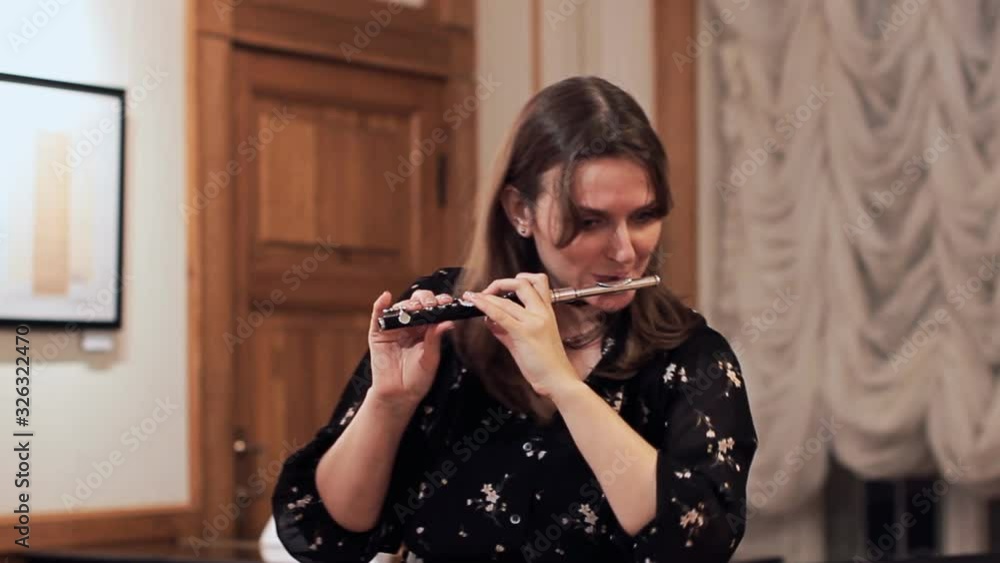 Young woman playing a piccolo flute, closeup portrait of a musician ...