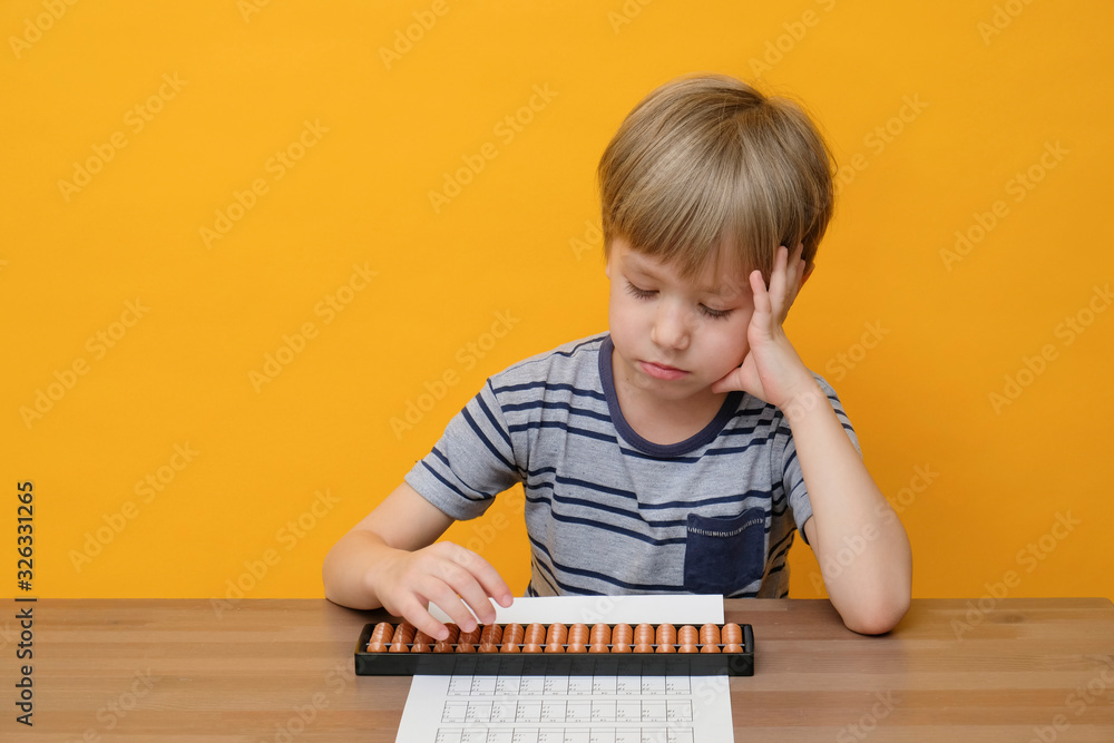 Little boy doing simple Mathematics exercises with abacus scores ...