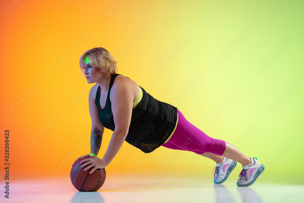 Young caucasian plus size female model's training on gradient orange ...