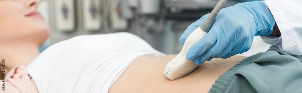 cropped view of doctor examining stomach of patient with ultrasound ...