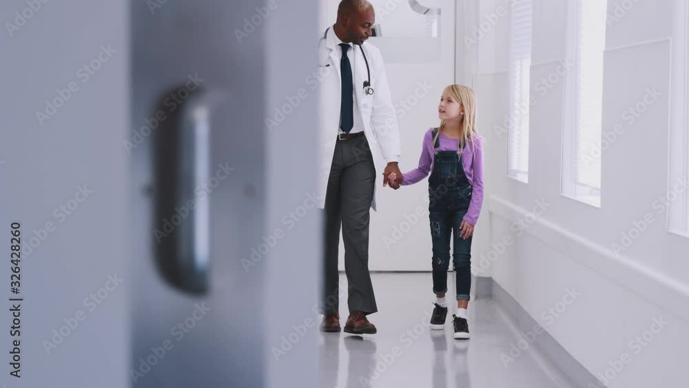 Male Paediatric Doctor Walking Along Hospital Corridor Holding Hands ...