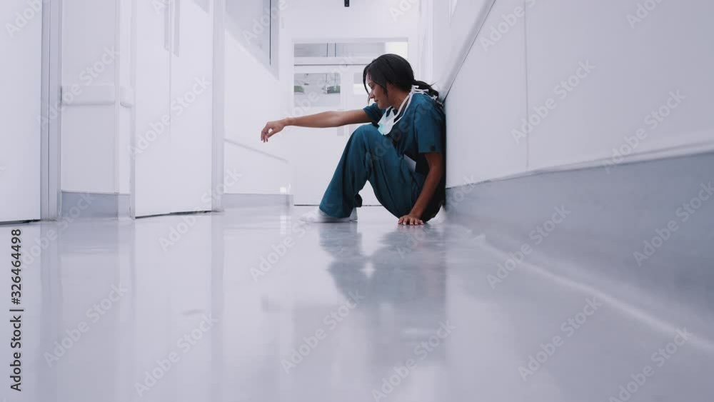 Stressed And Overworked Female Doctor Wearing Scrubs Sitting On Floor ...