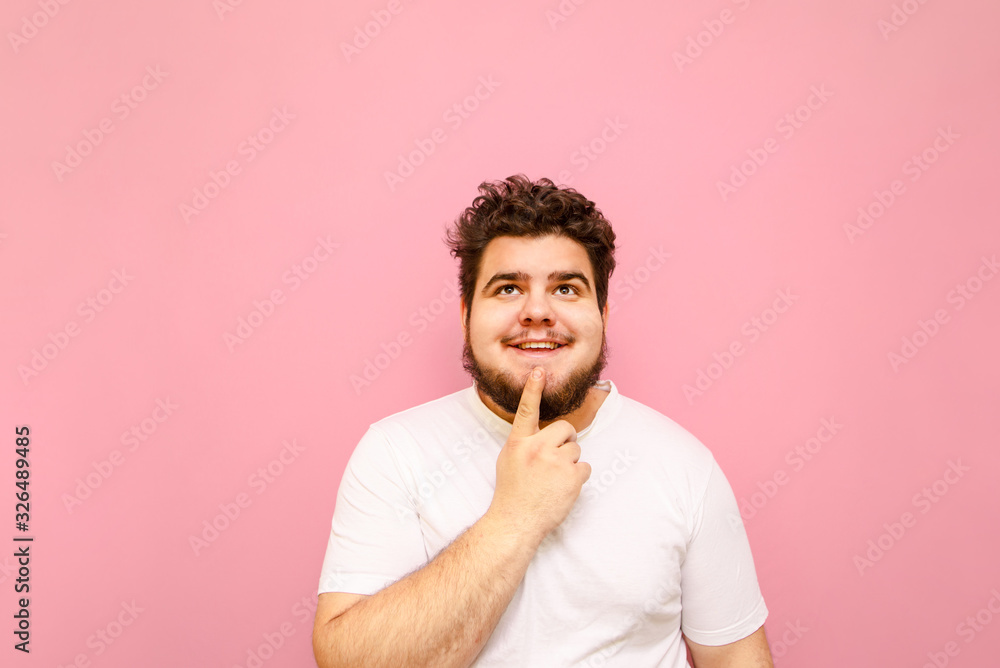 Portrait of a funny happy fat man in white t-shirt on a pink background ...