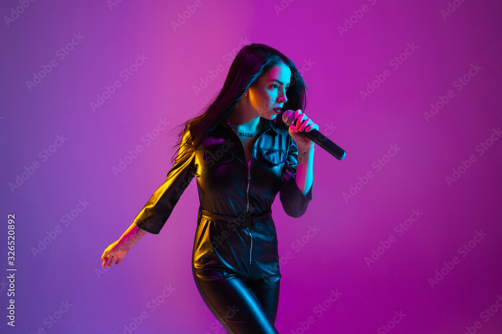 Caucasian female singer portrait isolated on purple studio background ...