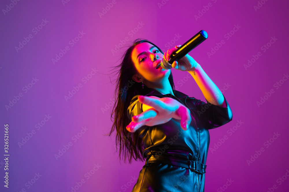 Caucasian female singer portrait isolated on purple studio background ...