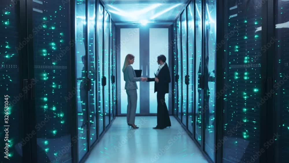 Two professional women server engineers inside server room, shaking ...