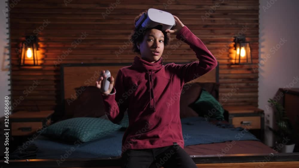 Scared teenage boy leaving game taking off VR headset being shocked by ...