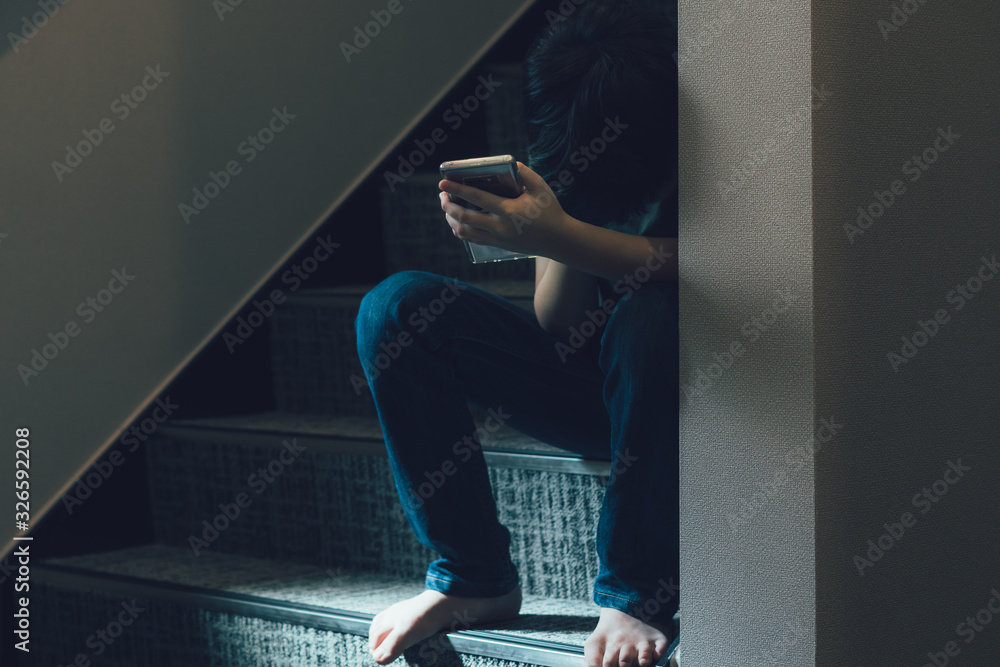 Young Asian preteen/teenage boy sit on stair at home, cry and cover his ...