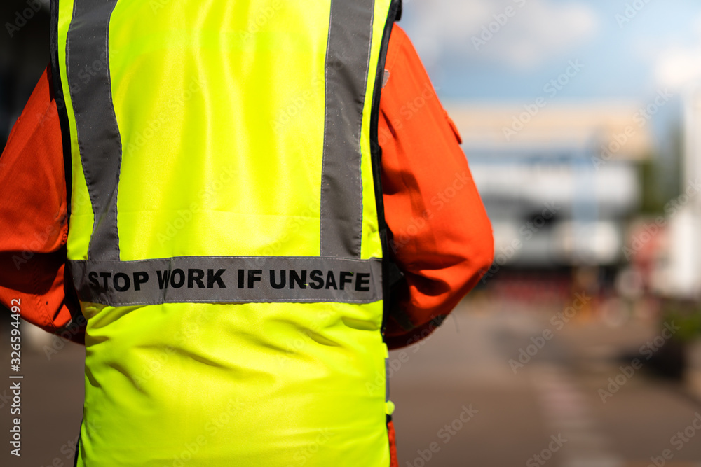 Close-up at "Stop work if unsafe" sign label on back of reflective vest ...
