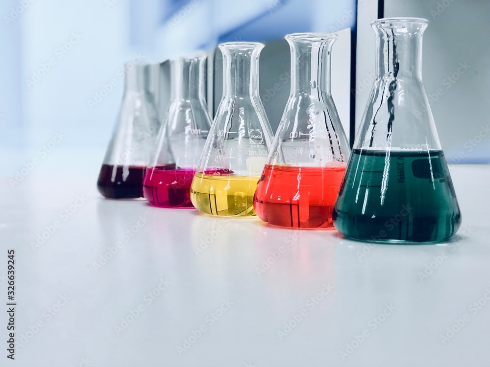 The Erlenmeyer or Conical flask on bench laboratory, with colorful ...