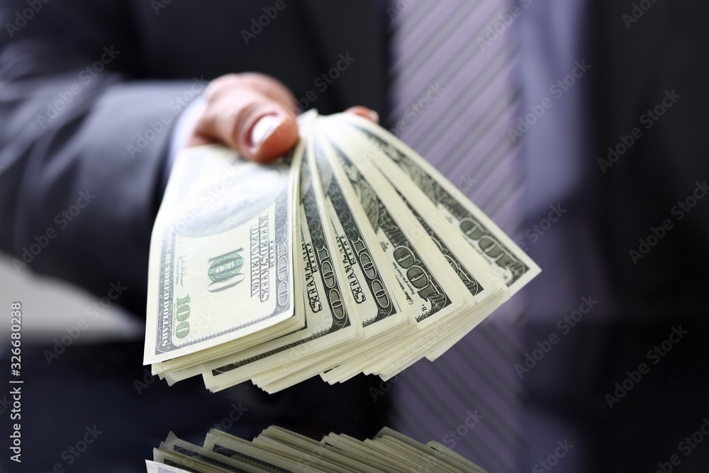 Man in suit and tie hold in arm pack of hundred dollar bills closeup ...