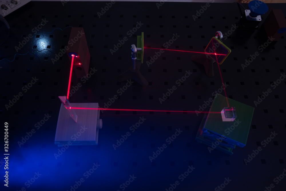 Experiment in optic lab with laser device. Red laser on optical table ...