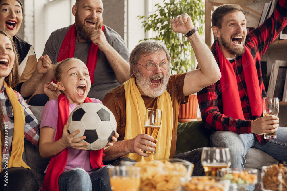Excited, happy big family watching football, soccer match on the couch ...