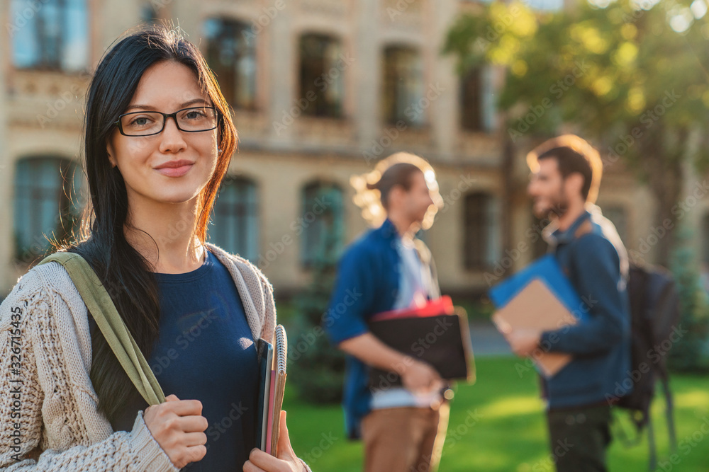 Caucasian female college student on modern campus with friends on ...