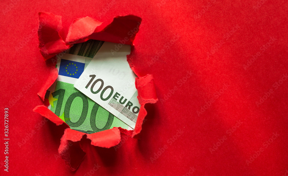 Euro banknote coming out of a torn paper over red background.Concept ...