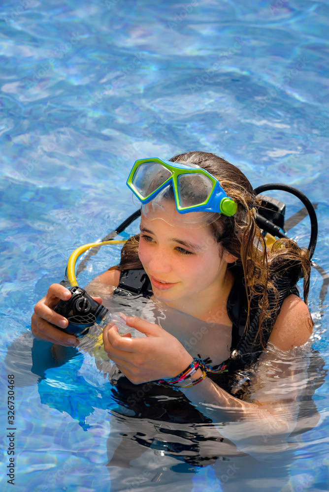 beautiful young woman taking a scuba diving lesson in swimming pool ...