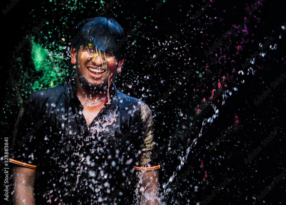 Young man playing holi with water. water splashing on his face. holi is ...