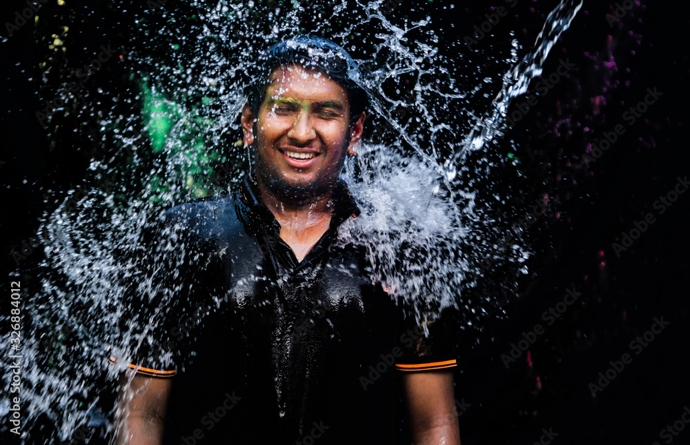 Young man playing holi with water. water splashing on his face. holi is ...