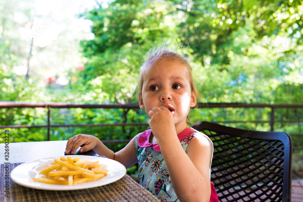 child eats french fries. not healthy food Stock Photo | Adobe Stock