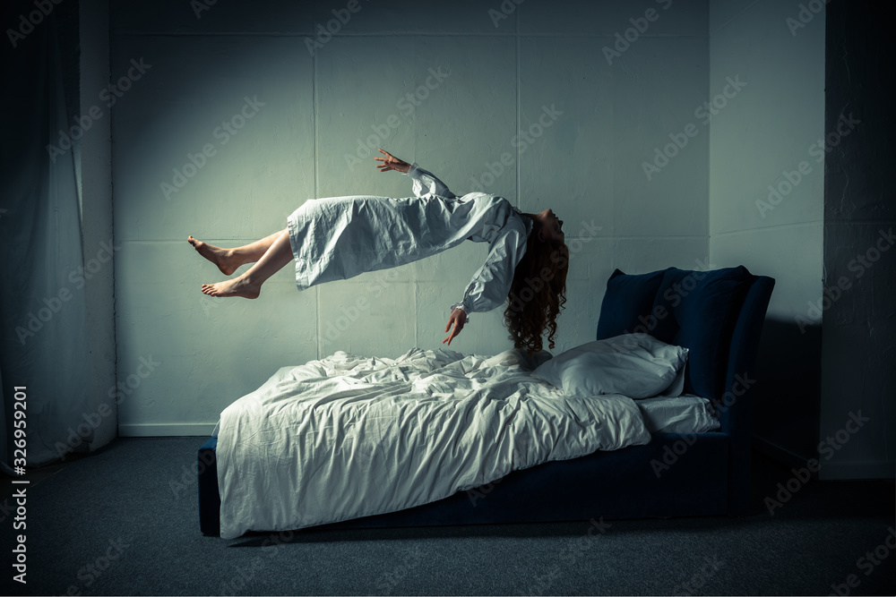 creepy woman in nightgown sleeping and levitating over bed Stock Photo ...