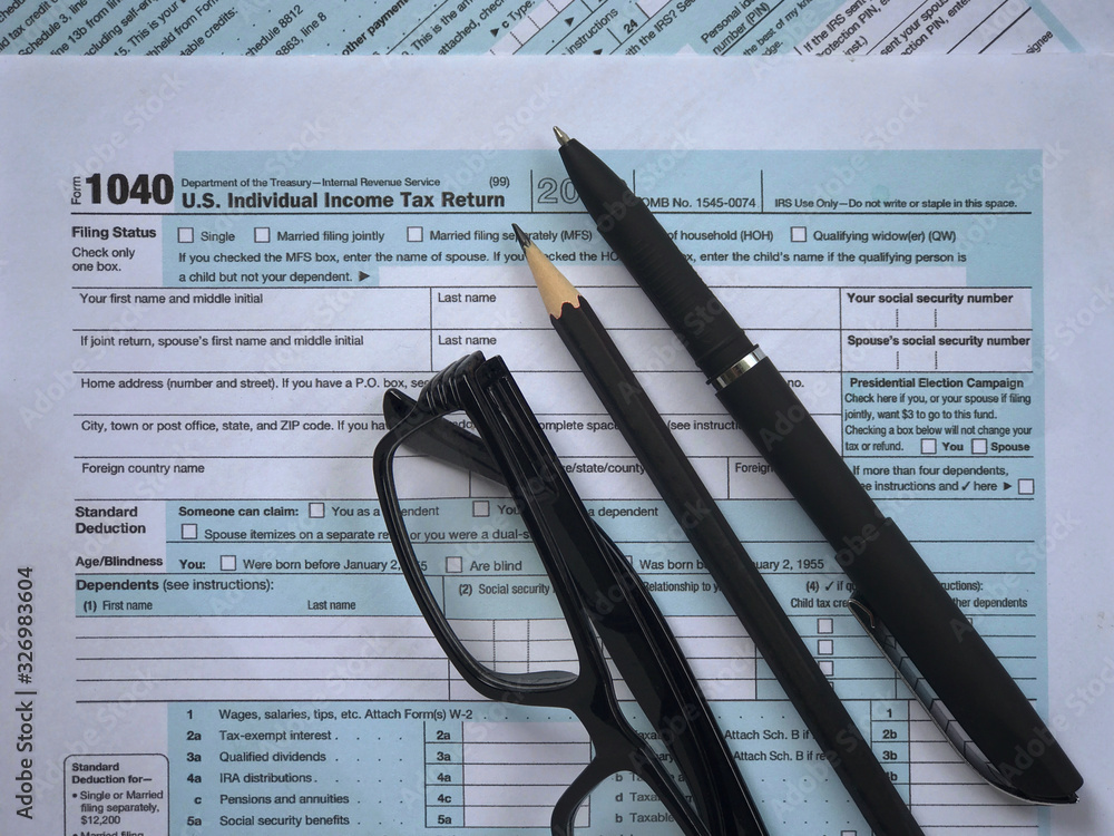 Tax-filling concept - A pencil, a pen, eyeglasses and featuring half of ...