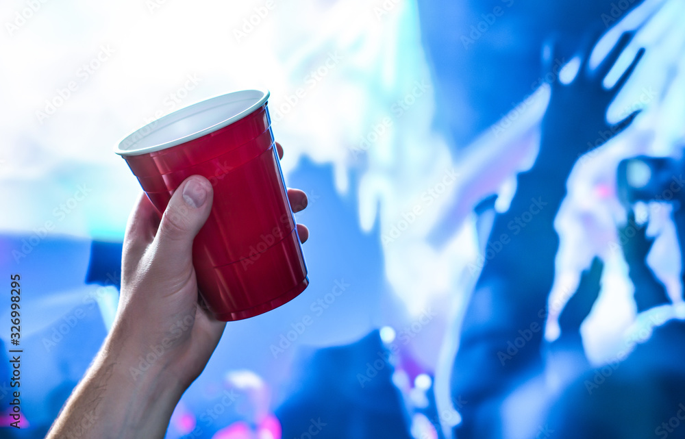 Red party cup in hand in night club, bar or college student event ...