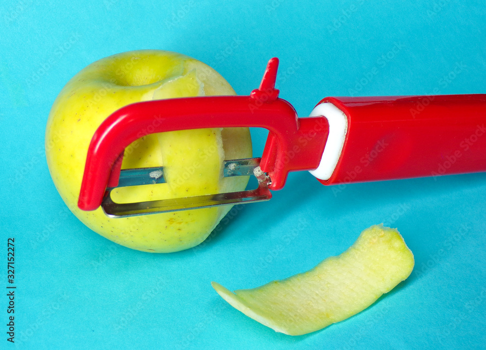 Apple with a peeler and pieces of skin on a blue background. Green ...