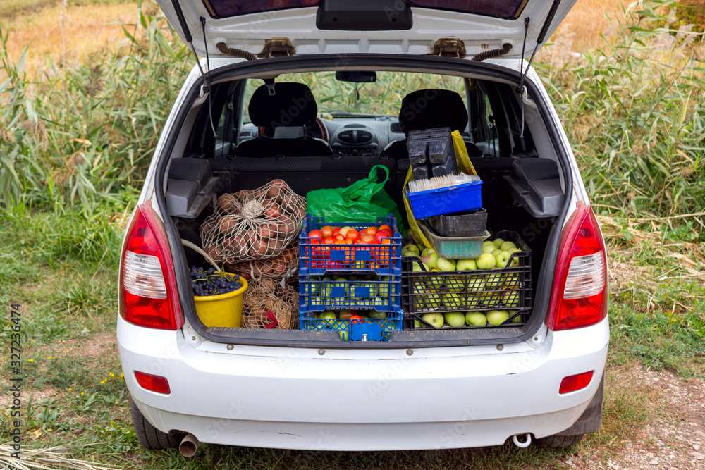 vegetables in boxes and bags loaded in the trunk of a car, harvesting ...