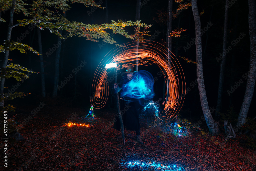 Sorcerer (magician) casting a spell while standing in the magical woods ...