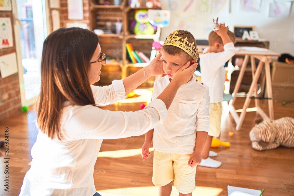 Beautiful teacher and toddlers playing with king crown around lots of ...