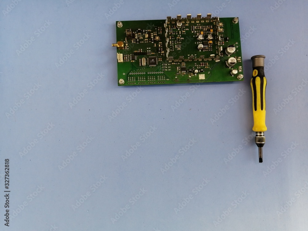 Green computer circuit board unscrewed with a screwdriver for repair on ...