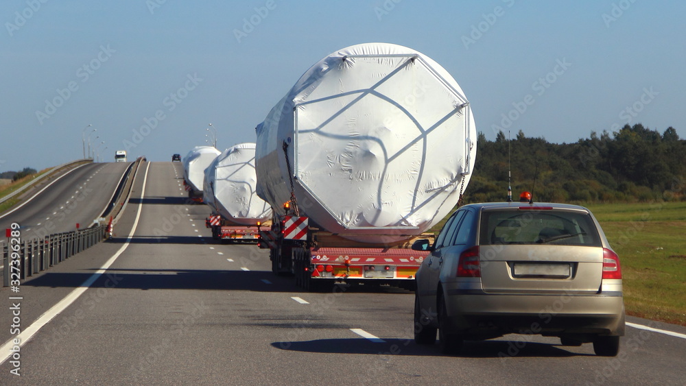 Oversize trucks convoy with escort car driving on suburban highway road ...