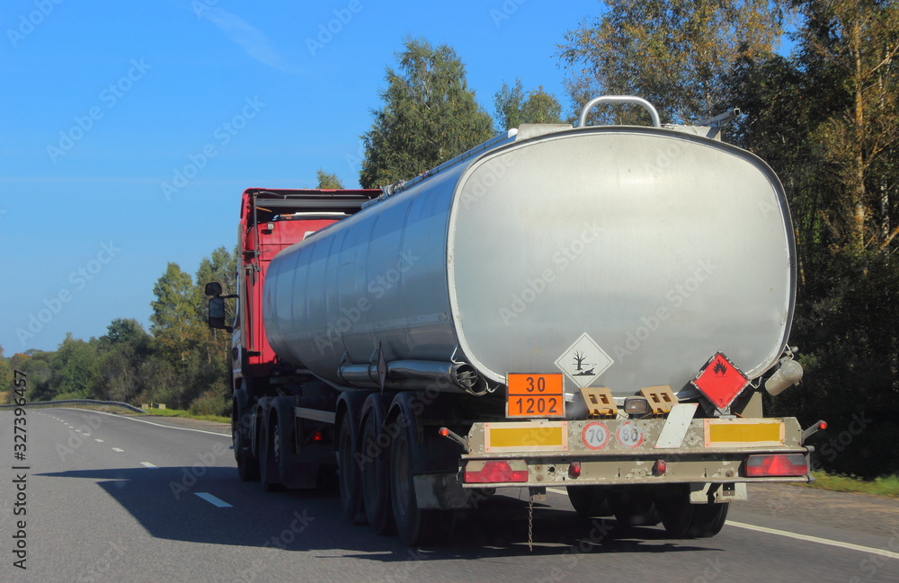 Oil tank semi truck with grey barrel moving on suburban asphalt highway ...