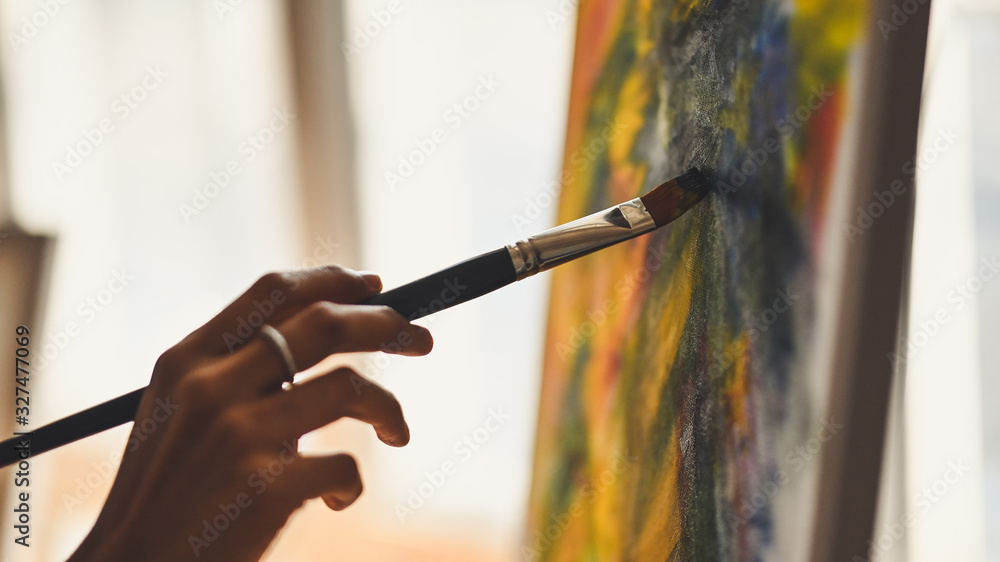 Cropped image of artist woman's hand drawing an oil color on canvas by ...