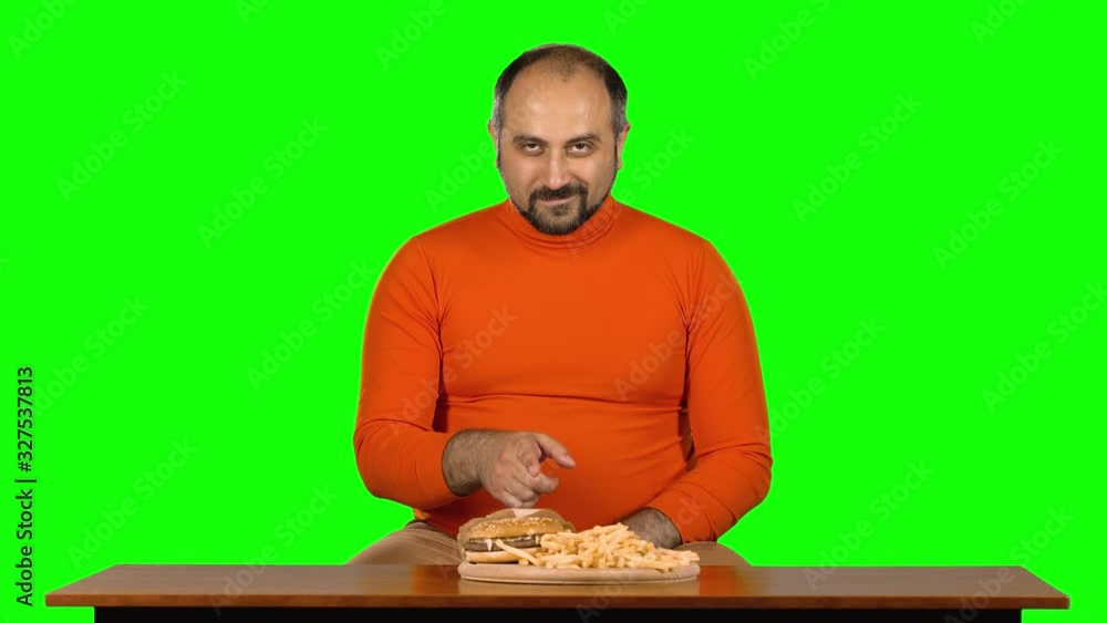 Caucasian man with overweight wants to eat a burger and french fries ...