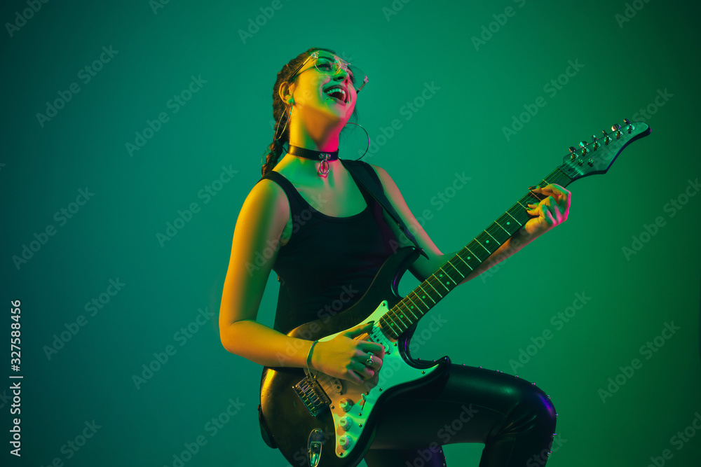Rockstar. Caucasian female guitarist portrait on green studio ...