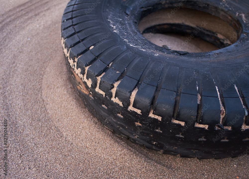 rubber dirty old vehicle tyre washed up on a sandy luxurious beach ...