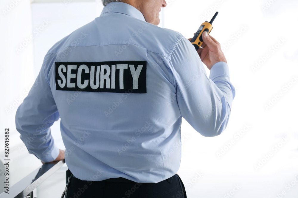 Professional security guard with portable radio set indoors, closeup ...