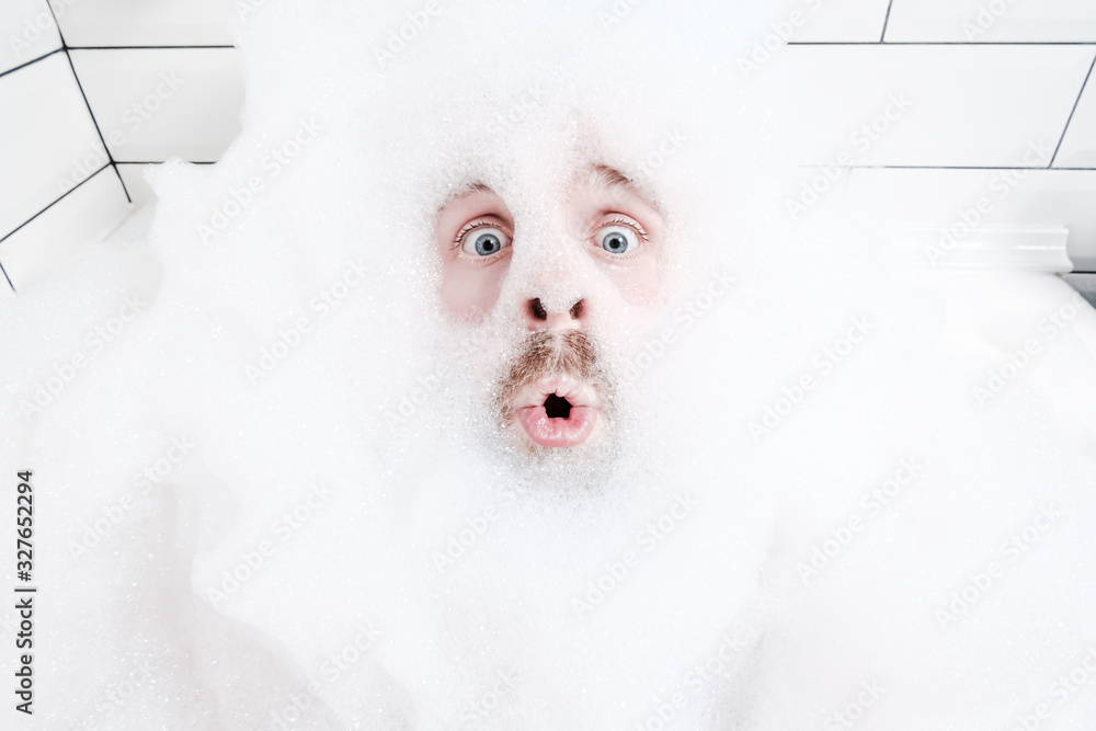 Surprised male face in a lush foam, only eyes and mouth are visible ...