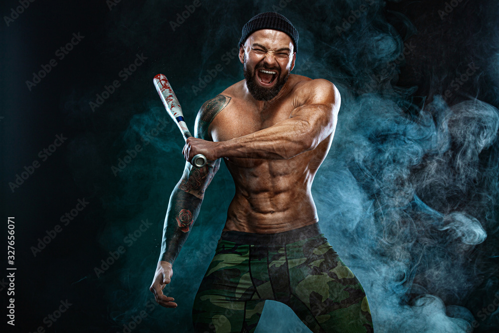 Strong and fit man bodybuilder with baseball bat shows abdominal ...