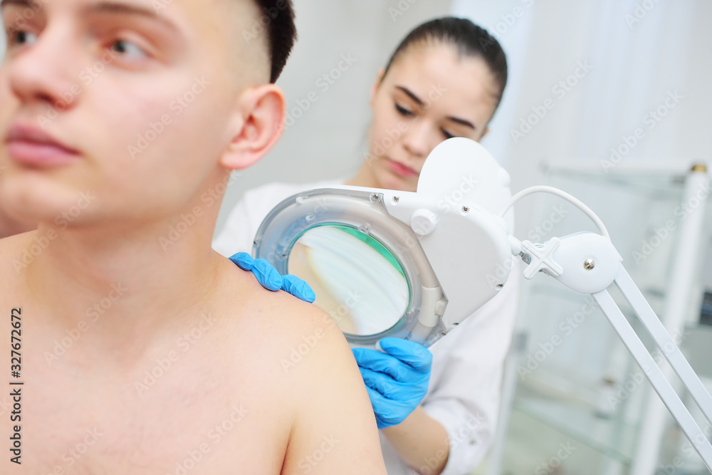 doctor dermatologist-a young woman examines the skin condition of a ...
