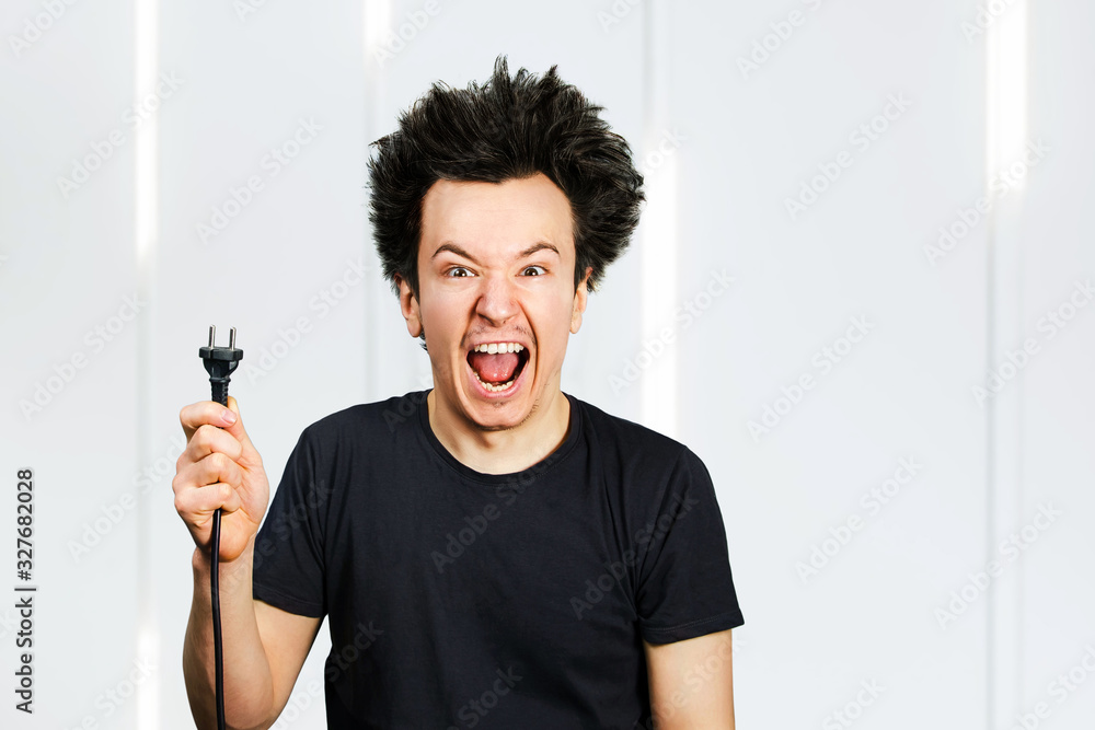 long hair guy holds an electric plug with a cable in his hand on a ...